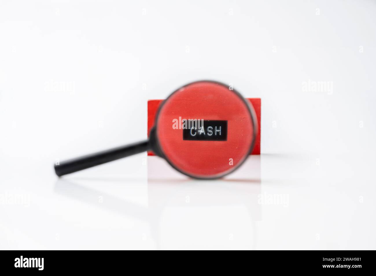 The magnifying glass focuses on CASH letters on a red background. The ...