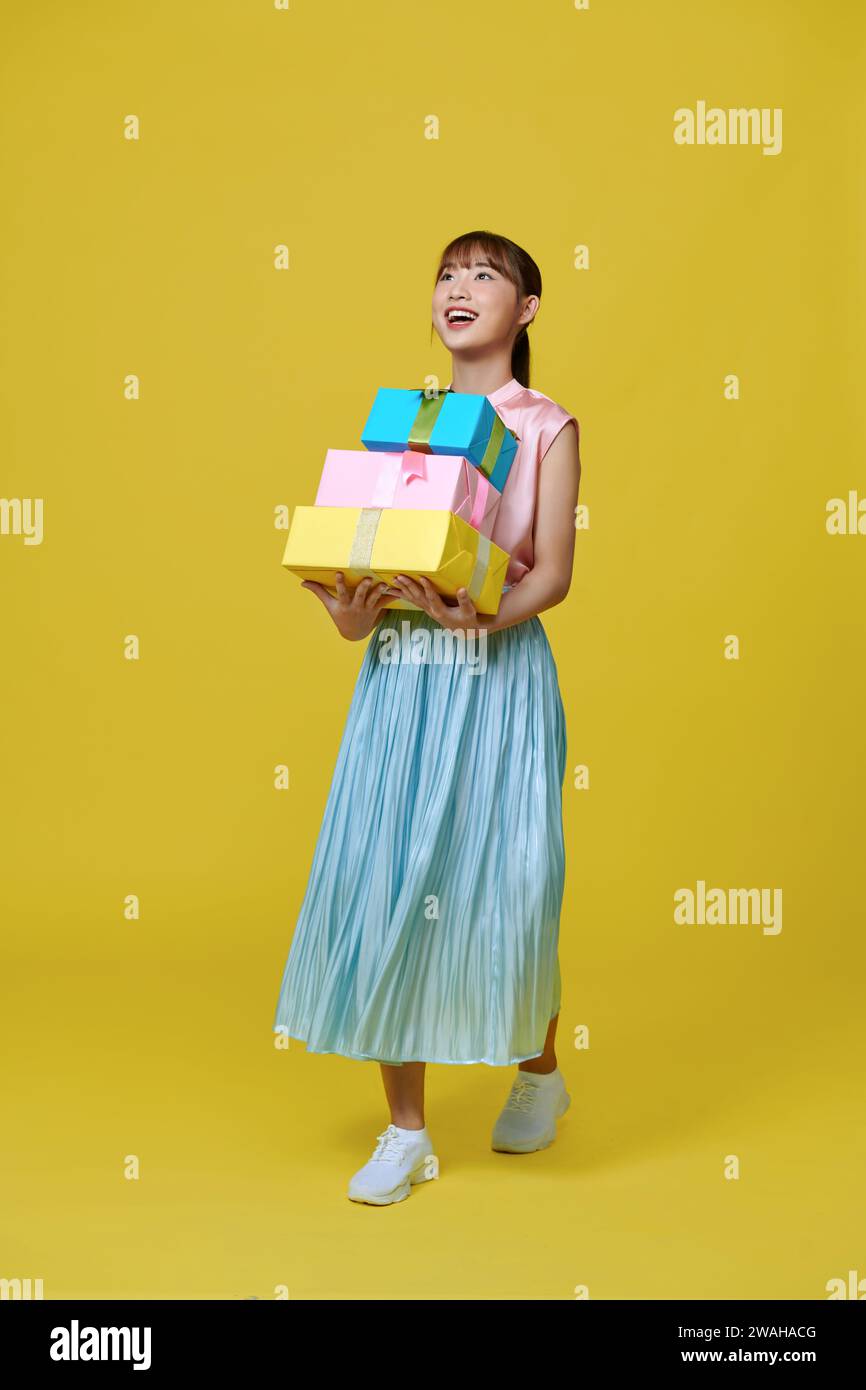 Attractive young girl in dress holding stack of gift boxes isolated ...