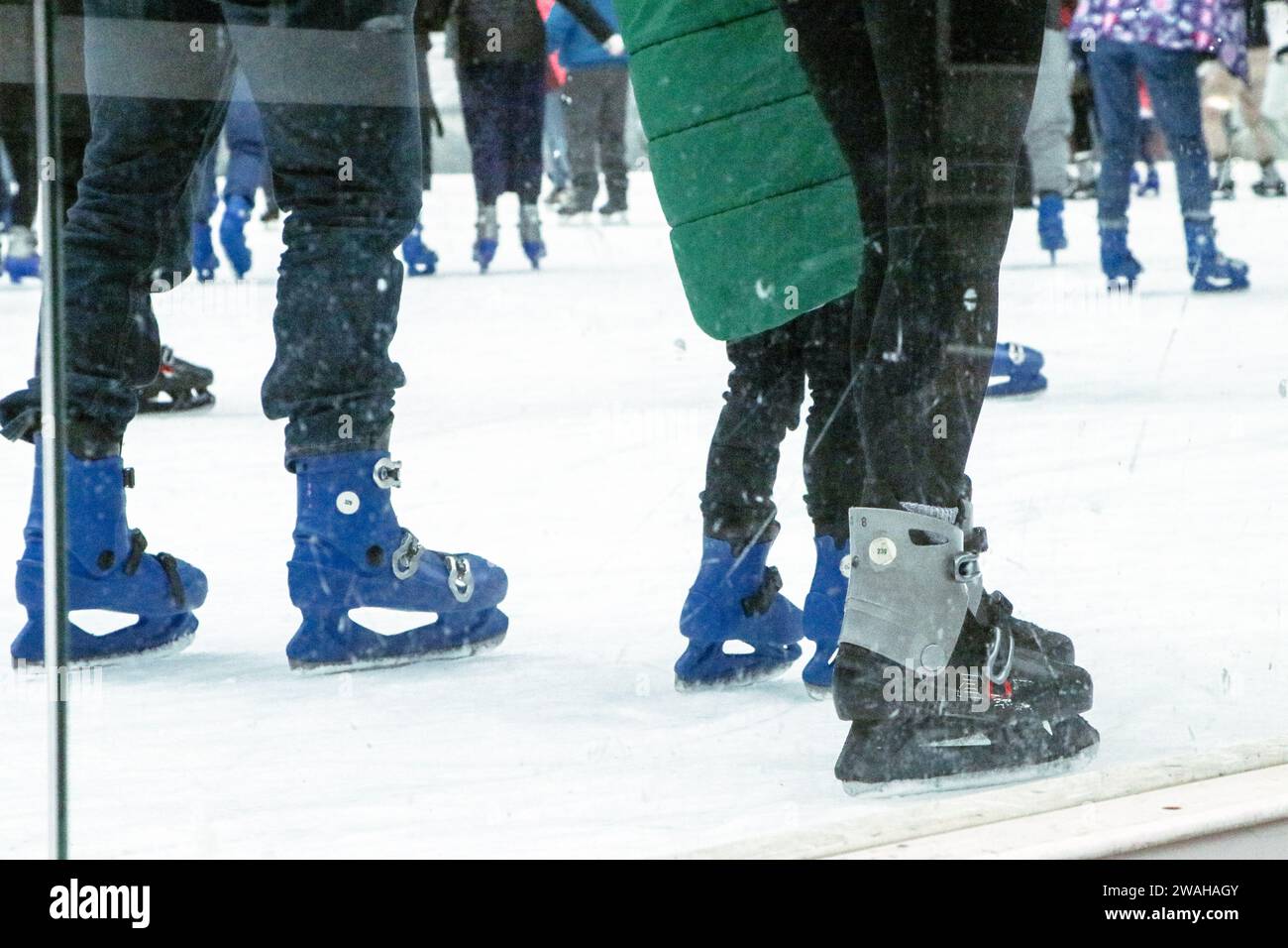 People standing on ice skates at the city skating arena enjoying the ...