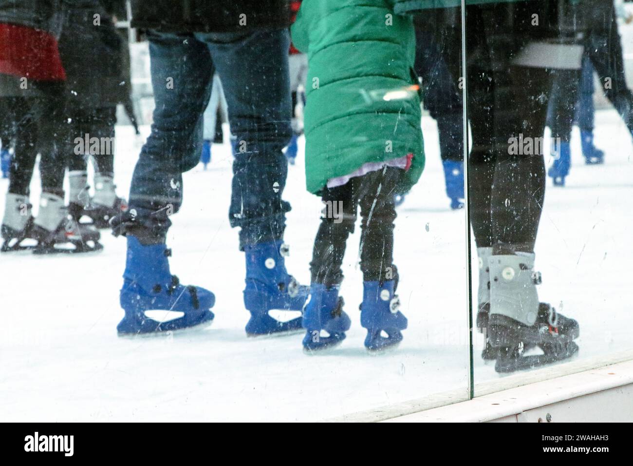 People standing on ice skates at the city skating arena enjoying the ...