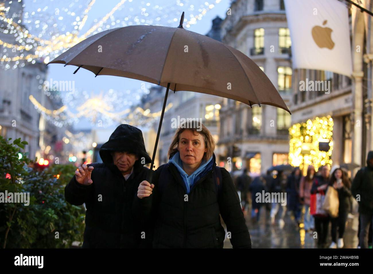 London, UK. 5th Jan, 2024. Shoppers shelter from the rain under their ...