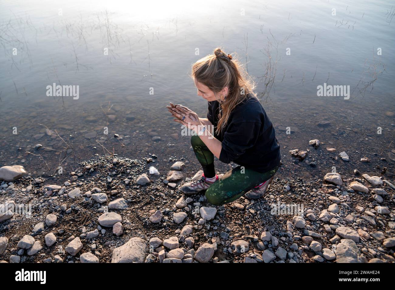 Woman putting mud on hands and face while enjoying outdoors in nature ...