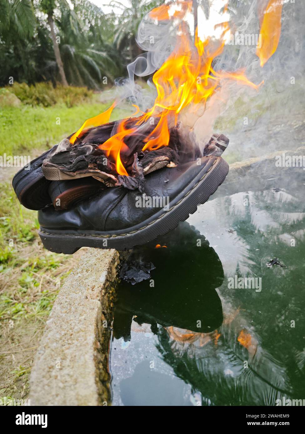old thrown away shoes on flame by the edge of the cylindrical concrete ...