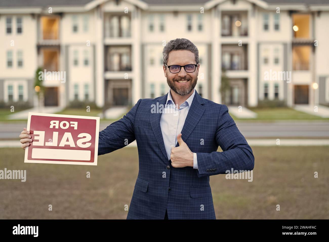 photo of realtor with for sale board showing thumb up gesture outdoor ...