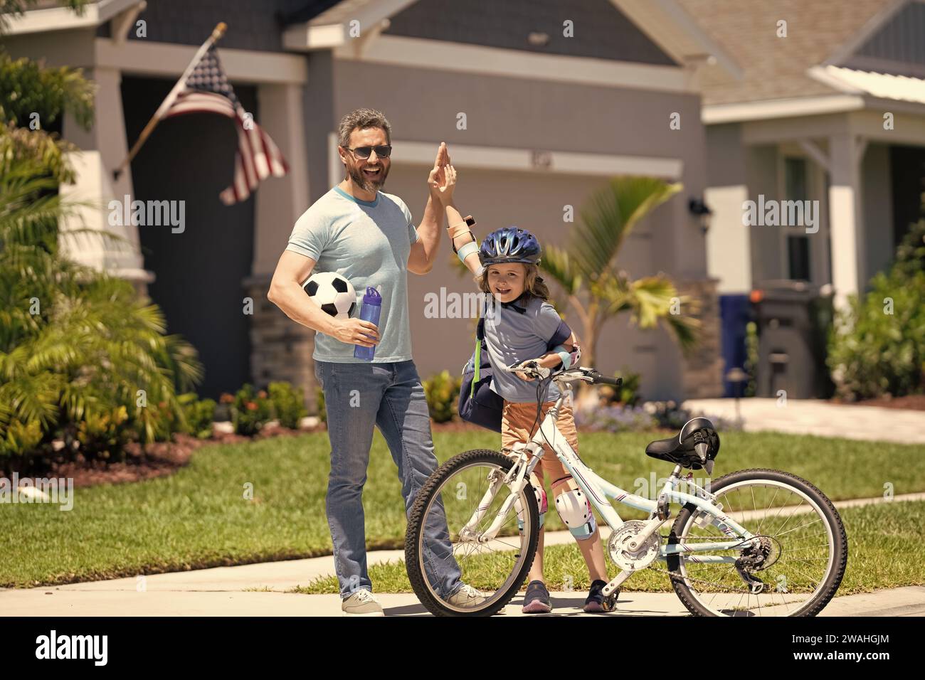 happy father guiding son first bike ride. Father and son sharing biking ...