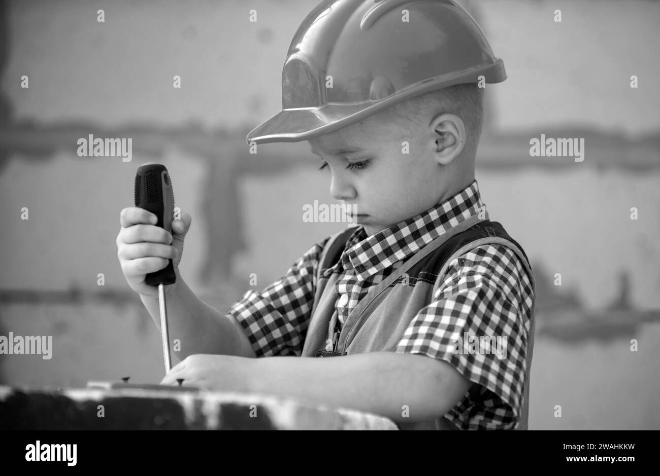 Kid boy twists bolt with screwdriver. Child repairman with repair tool ...