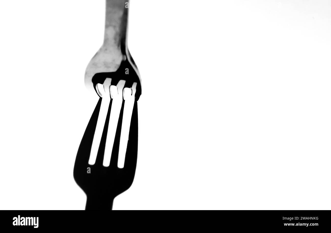 Single dinner fork standing vertically with hard shadow isolated on ...