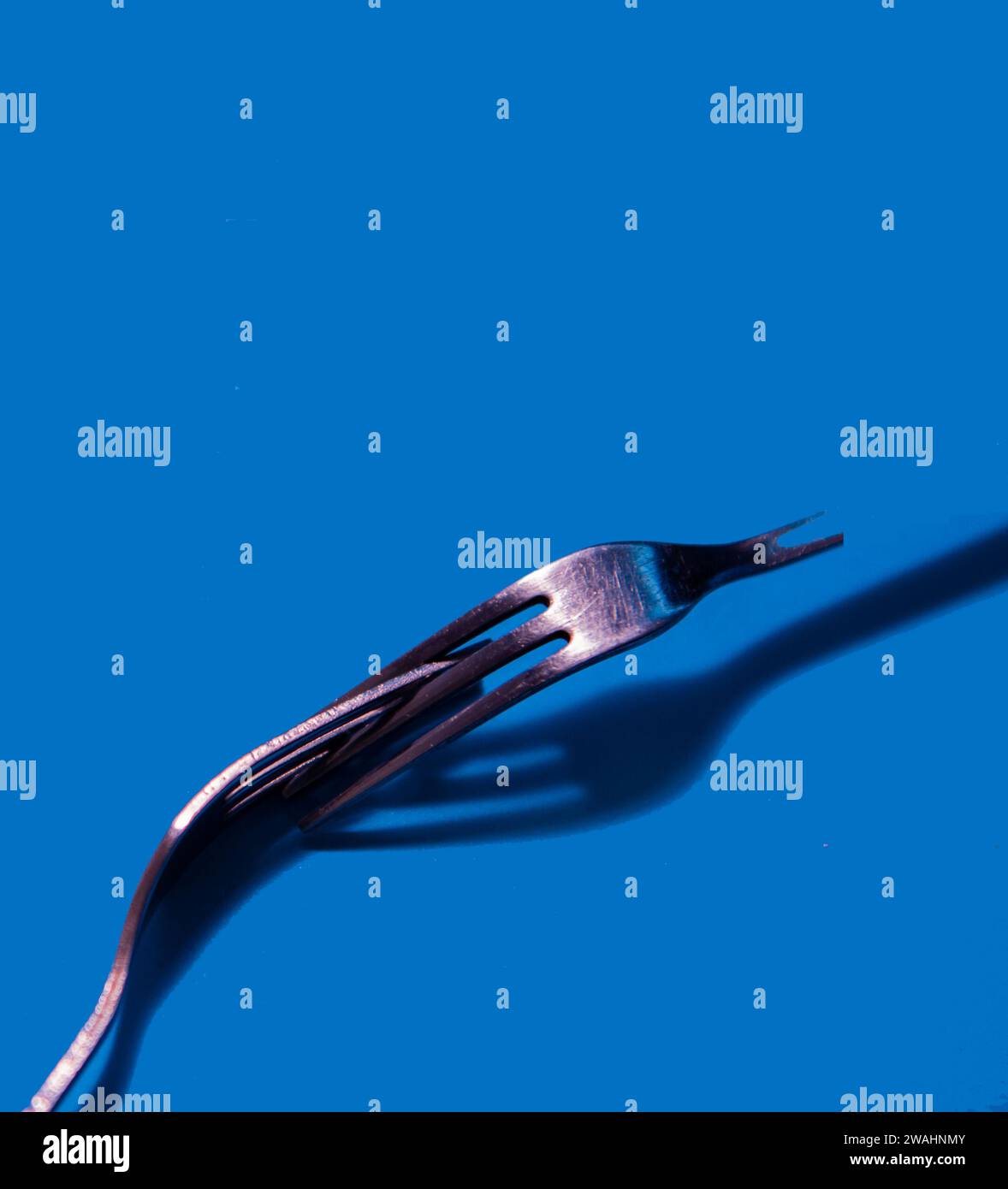 Two small three-tine forks laced together with handle of one cut out ...