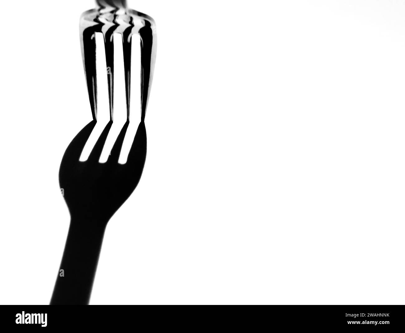 Single dinner fork standing vertically with hard shadow isolated on ...