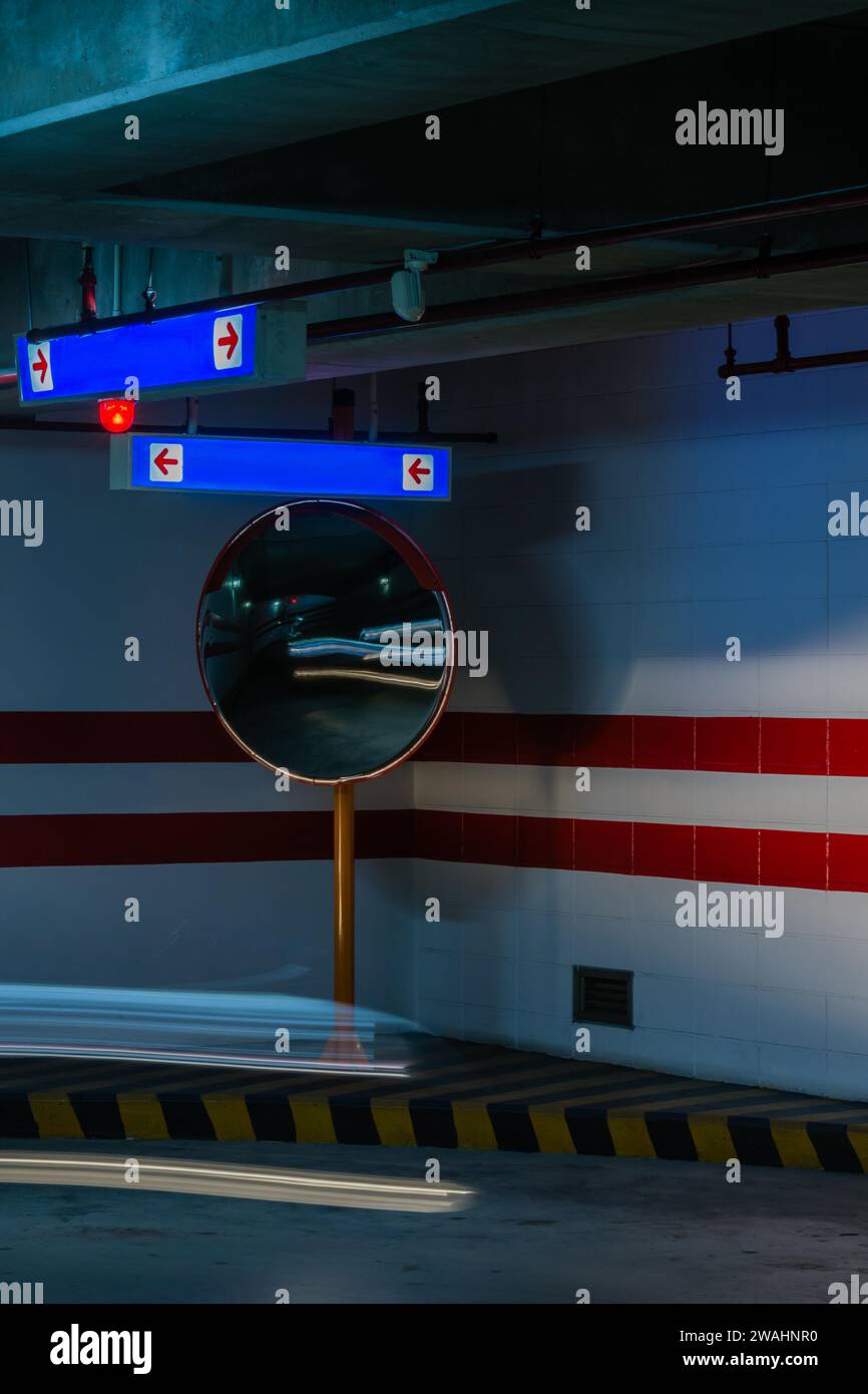 Light trails from moving car under large round parking garage mirror ...