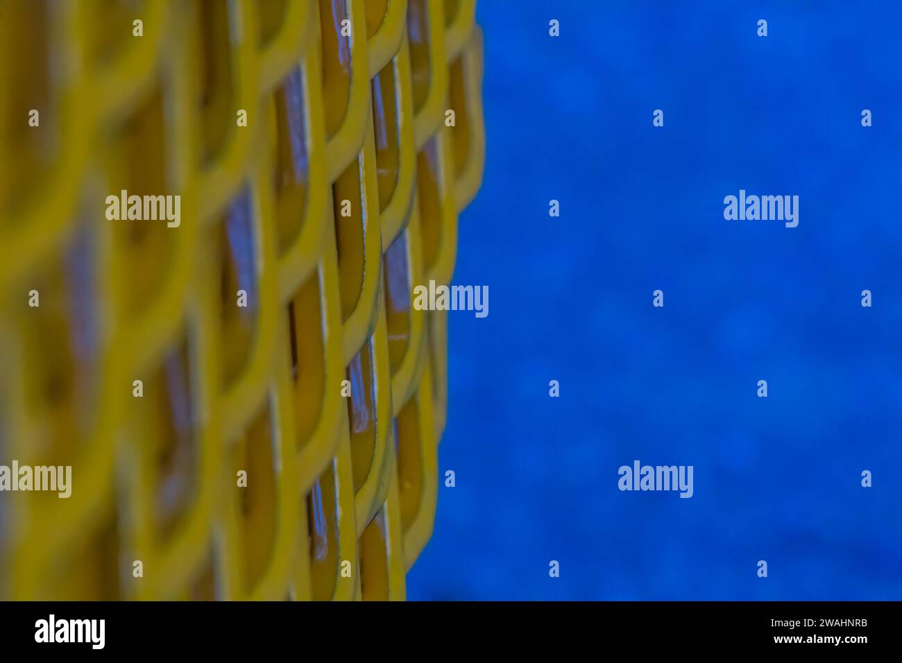 Macro of yellow metal grate on blue background with blur in both ...