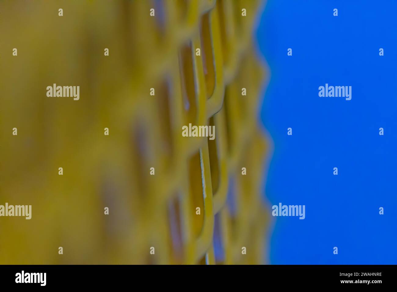 Macro of yellow metal grate on blue background with blur in both ...