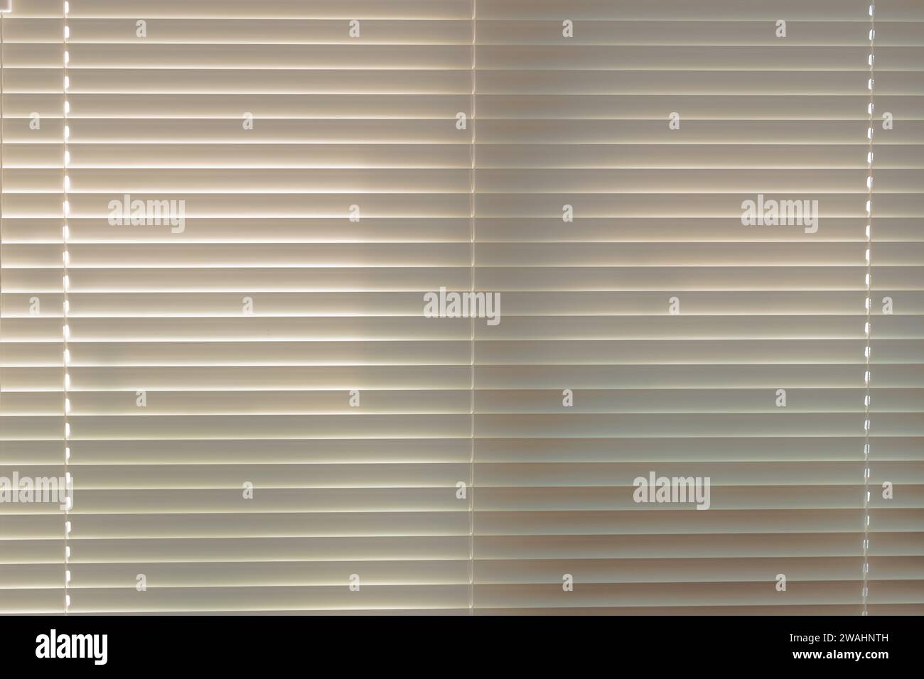 White window blinds with some shadows on window with sun shinning ...