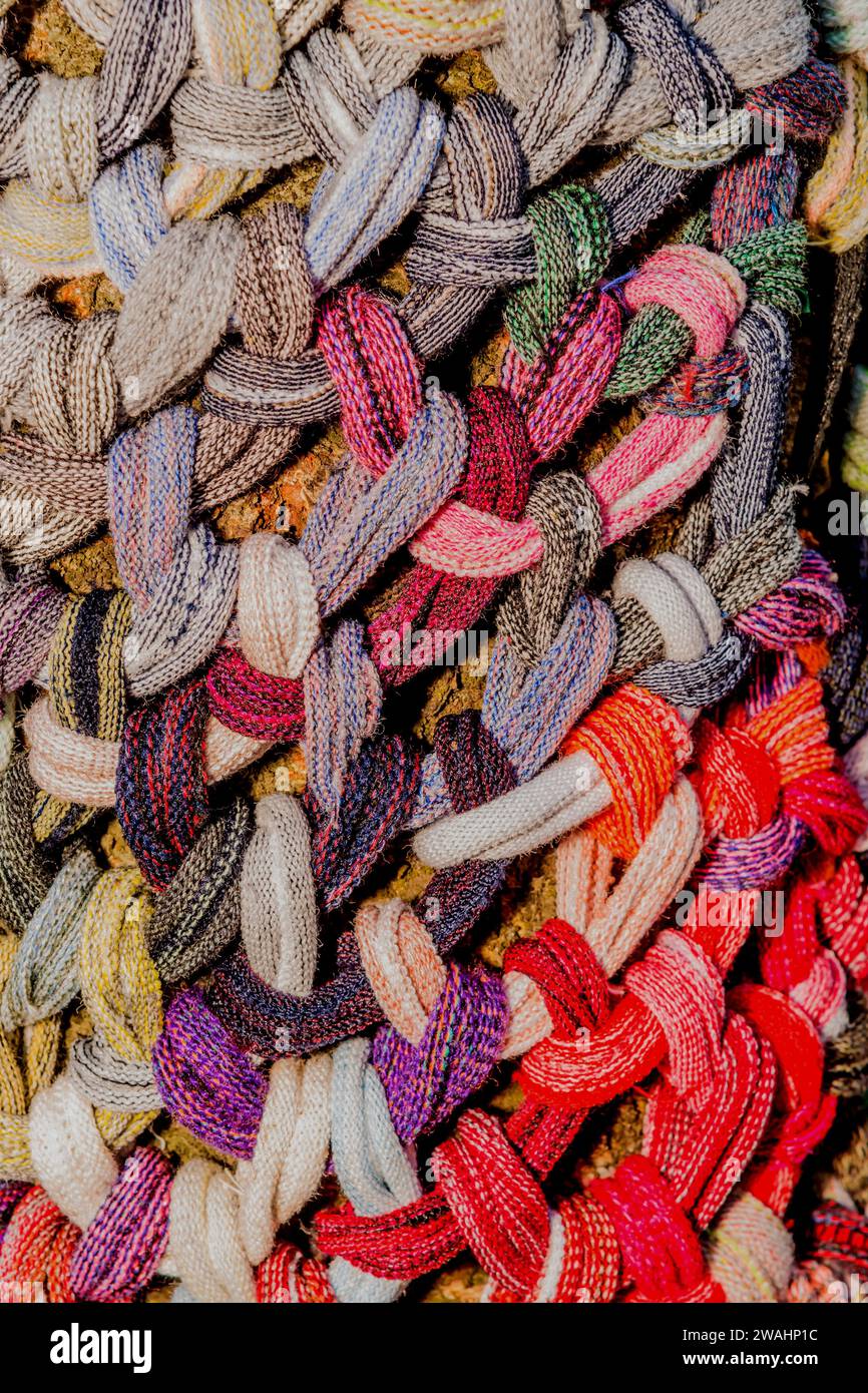 Yarn of various colors tied in loops around tree Stock Photo - Alamy