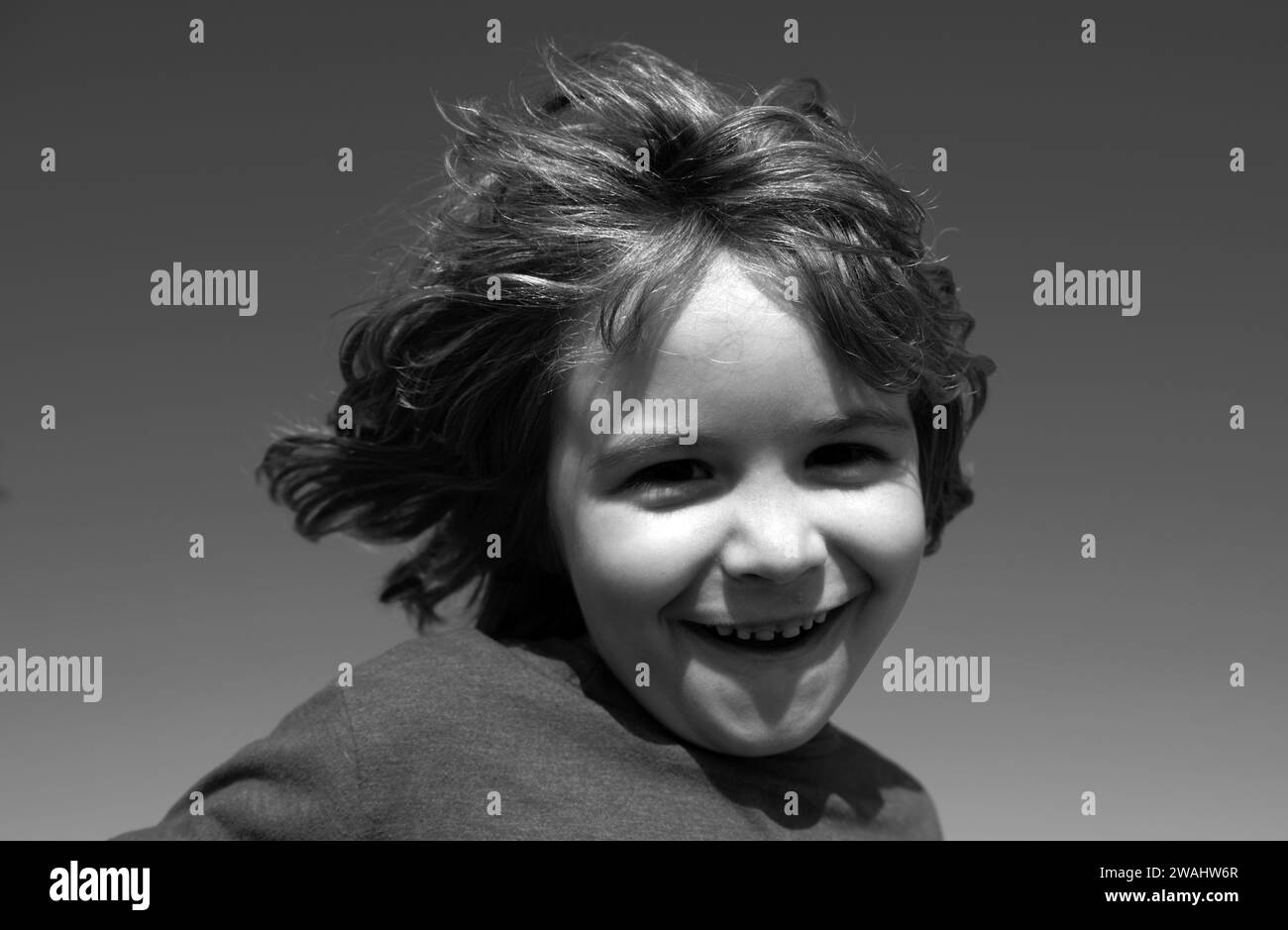 Portrait of a happy laughing child on blue sky with copy space. Close ...