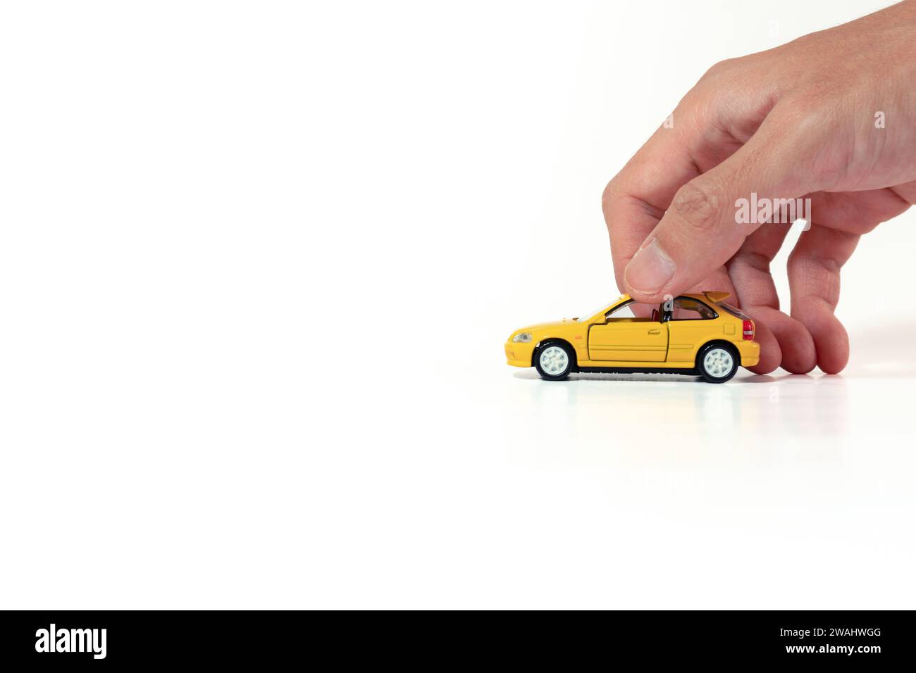 Hand holding a yellow toy car isolated on white background. After some ...