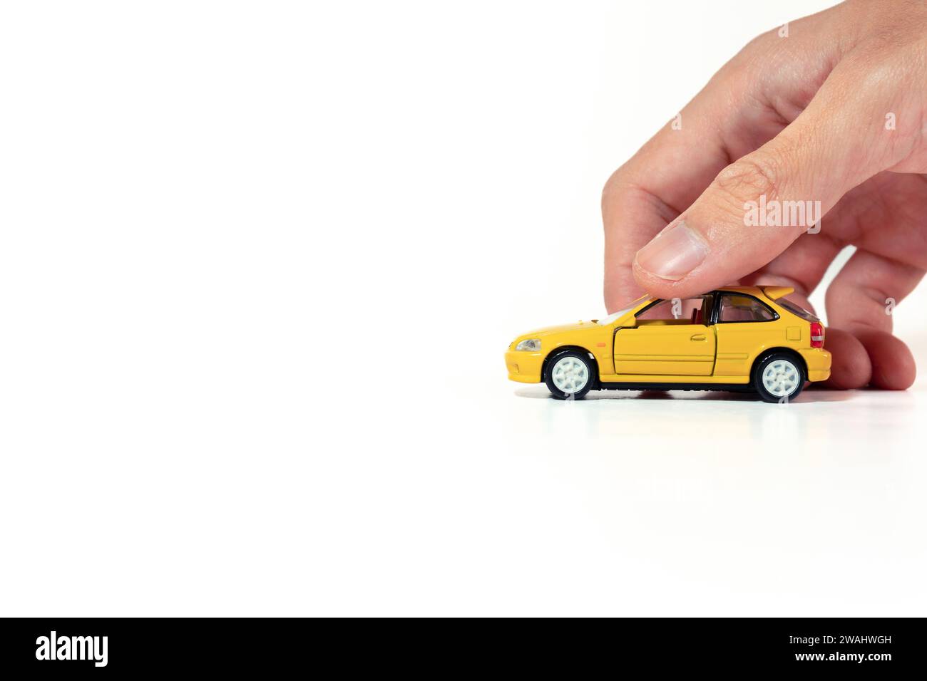 Hand holding a yellow toy car isolated on white background. After some ...