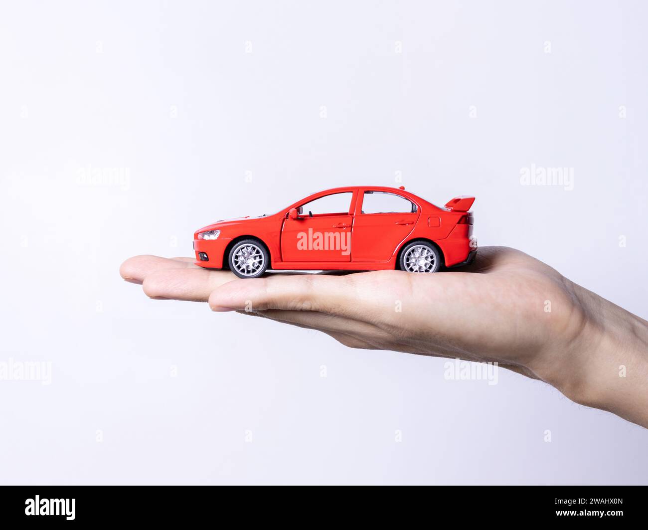 Hand holding a toy car isolated on gradient background. After some ...