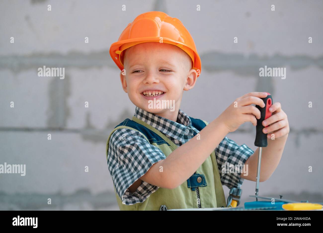 Little boy holding screwdriver. Happy smiling kid twists bolt with ...