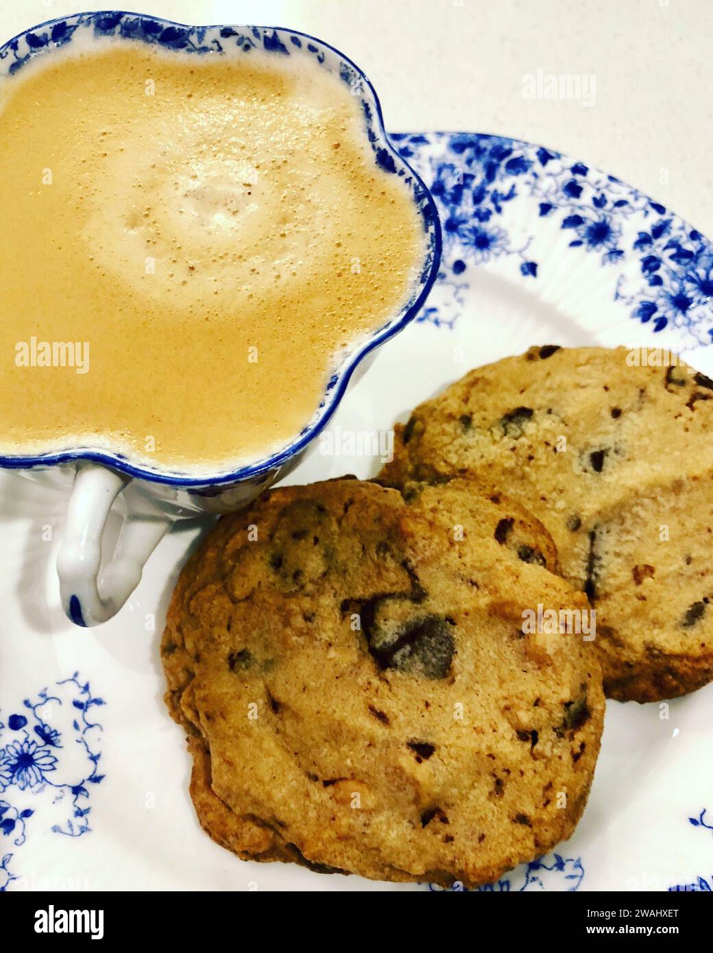 Two chocolate chip cookies and a cup of coffee on matching porcelain ...