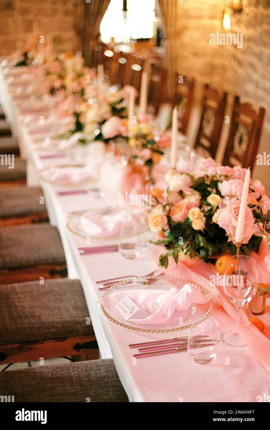 Invitations lie on knotted napkins on plates on a long festive table in ...