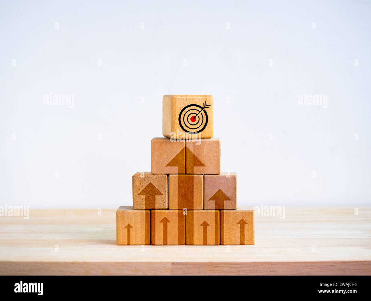 Target icon on top of wooden cube blocks stack as pyramid shape with rise up arrows on white ...