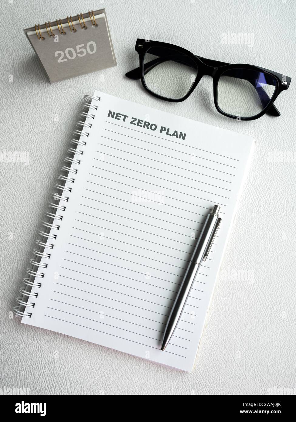 Words "Net Zero Plan" on blank vertical notepad page with pen, empty ...