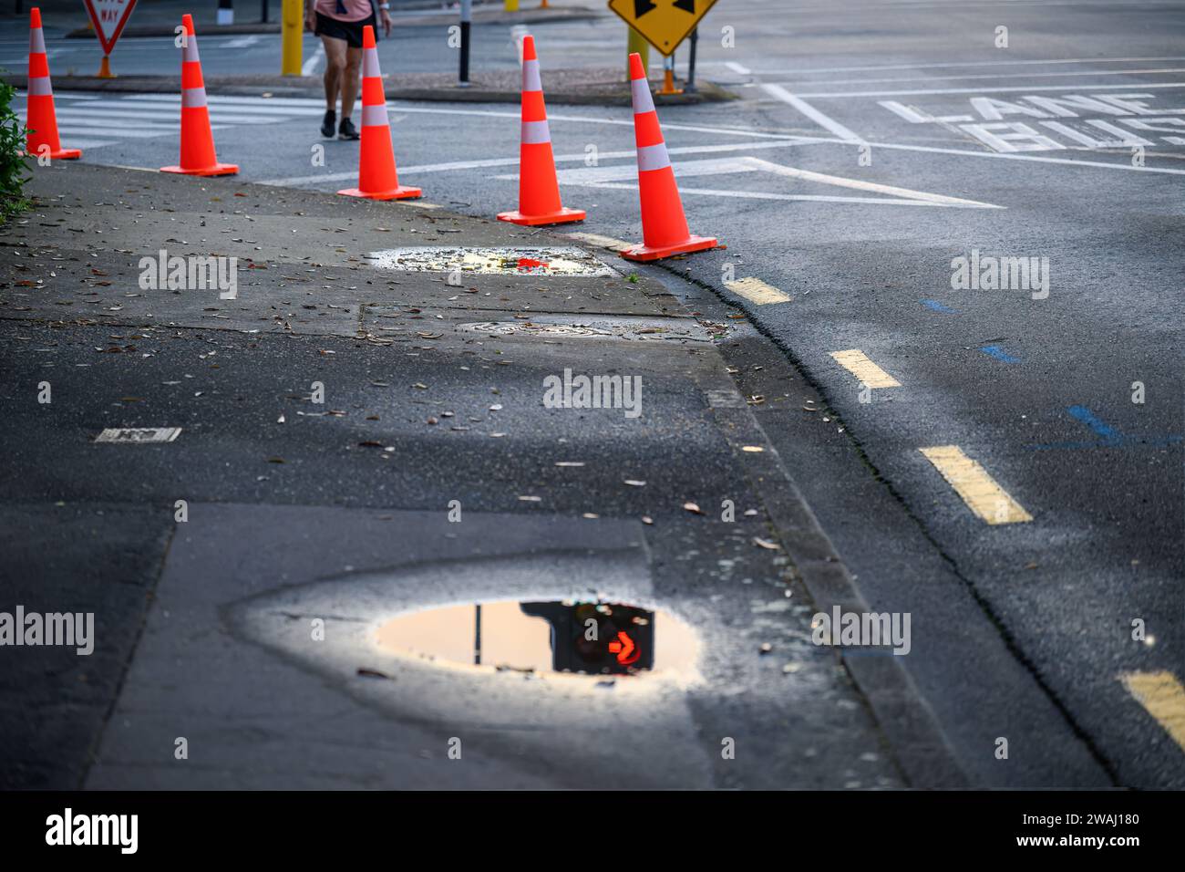 Orange traffic cones lining up the street. Red traffic arrow sign ...
