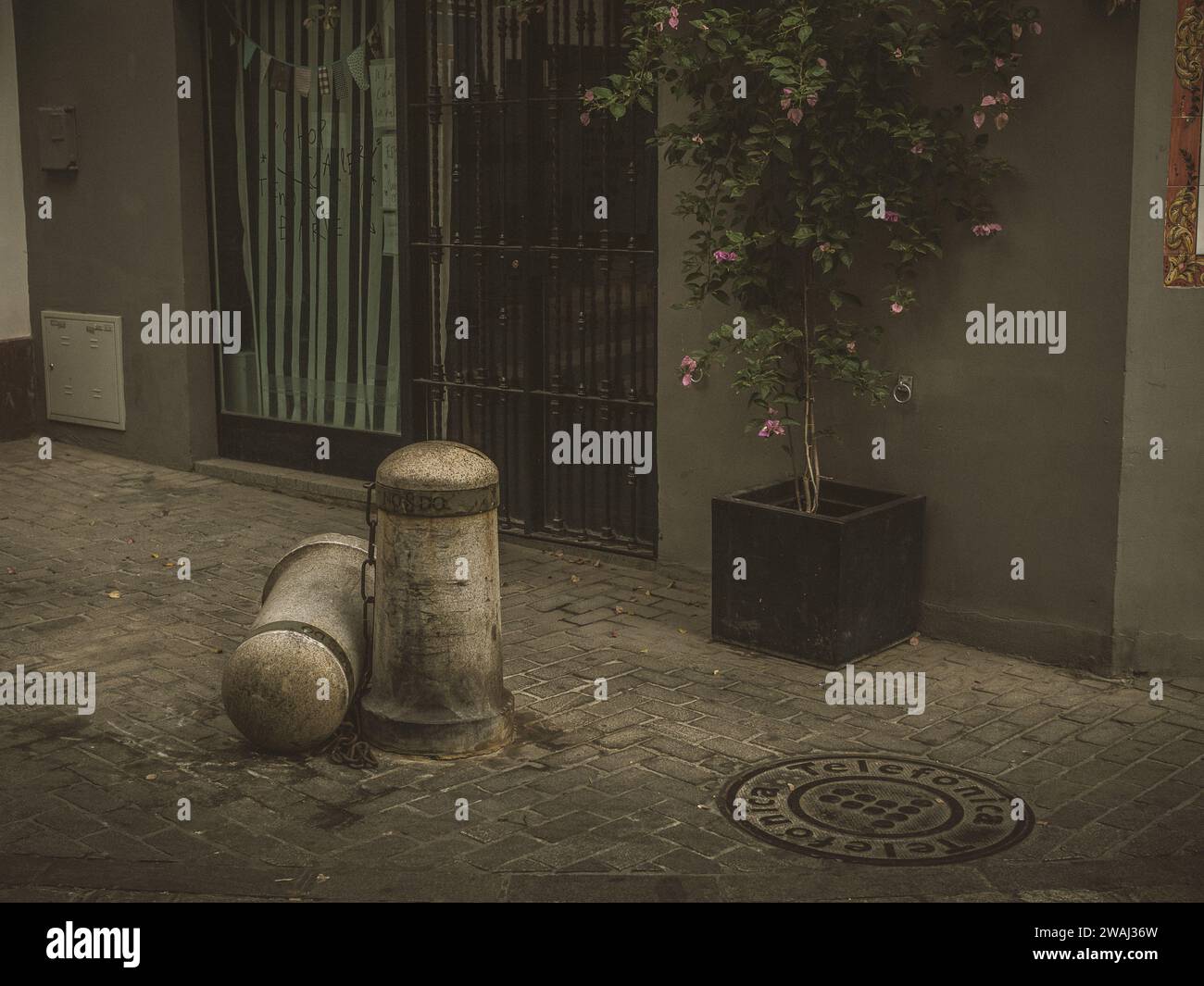 The two stone bollards chained together on a narrow street in Seville ...