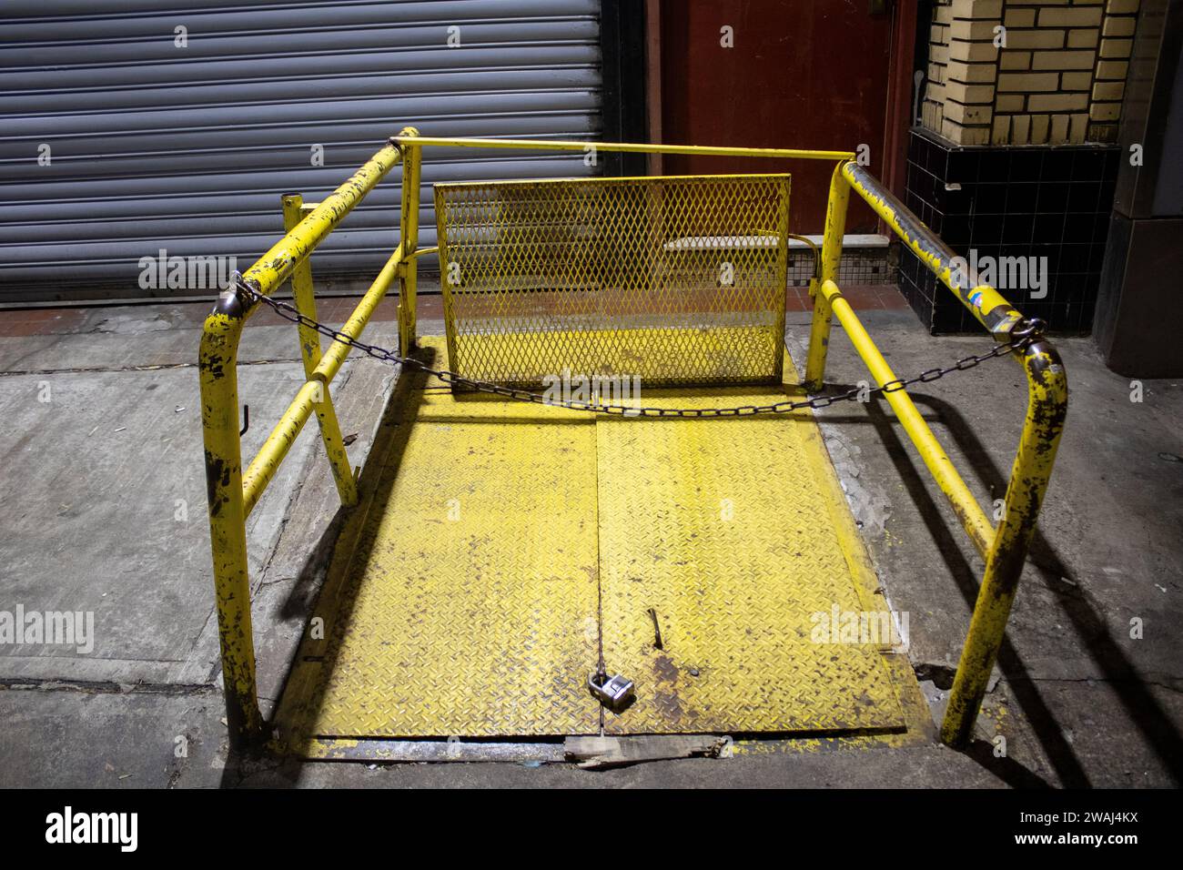 A closed metal gate with chains padlocked in the darkness of night in ...