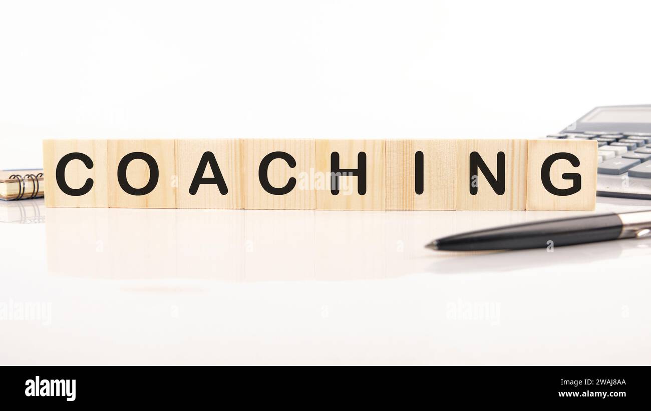 COACHING word assembled from wooden cubes next to a calculator, pen and ...