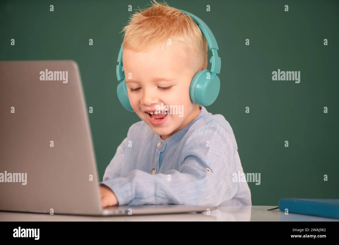 Happy child boy in headphones using a laptop and study online with ...