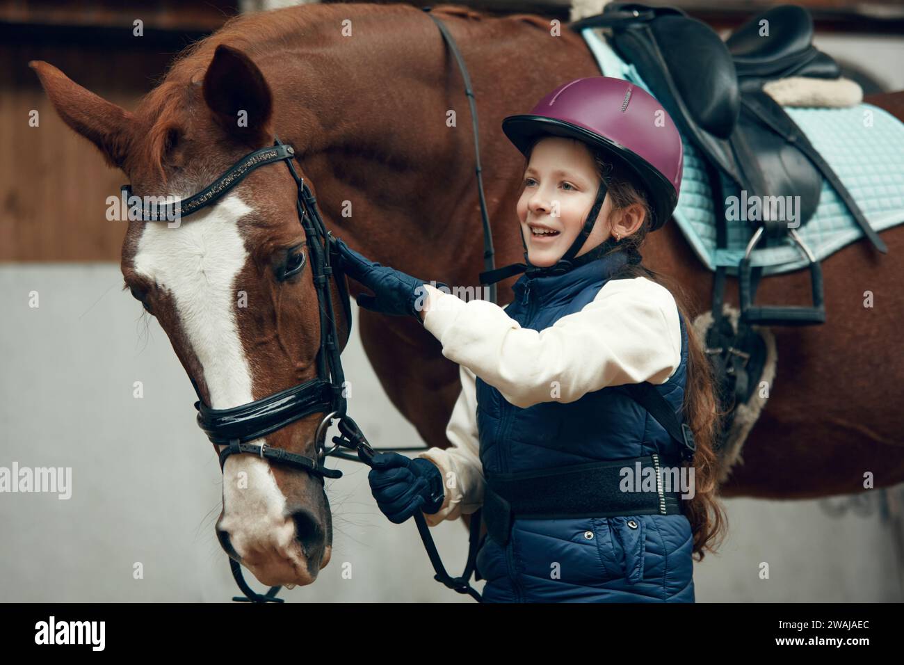 Little girl, kid in helmet taking care after horse, showing her love ...