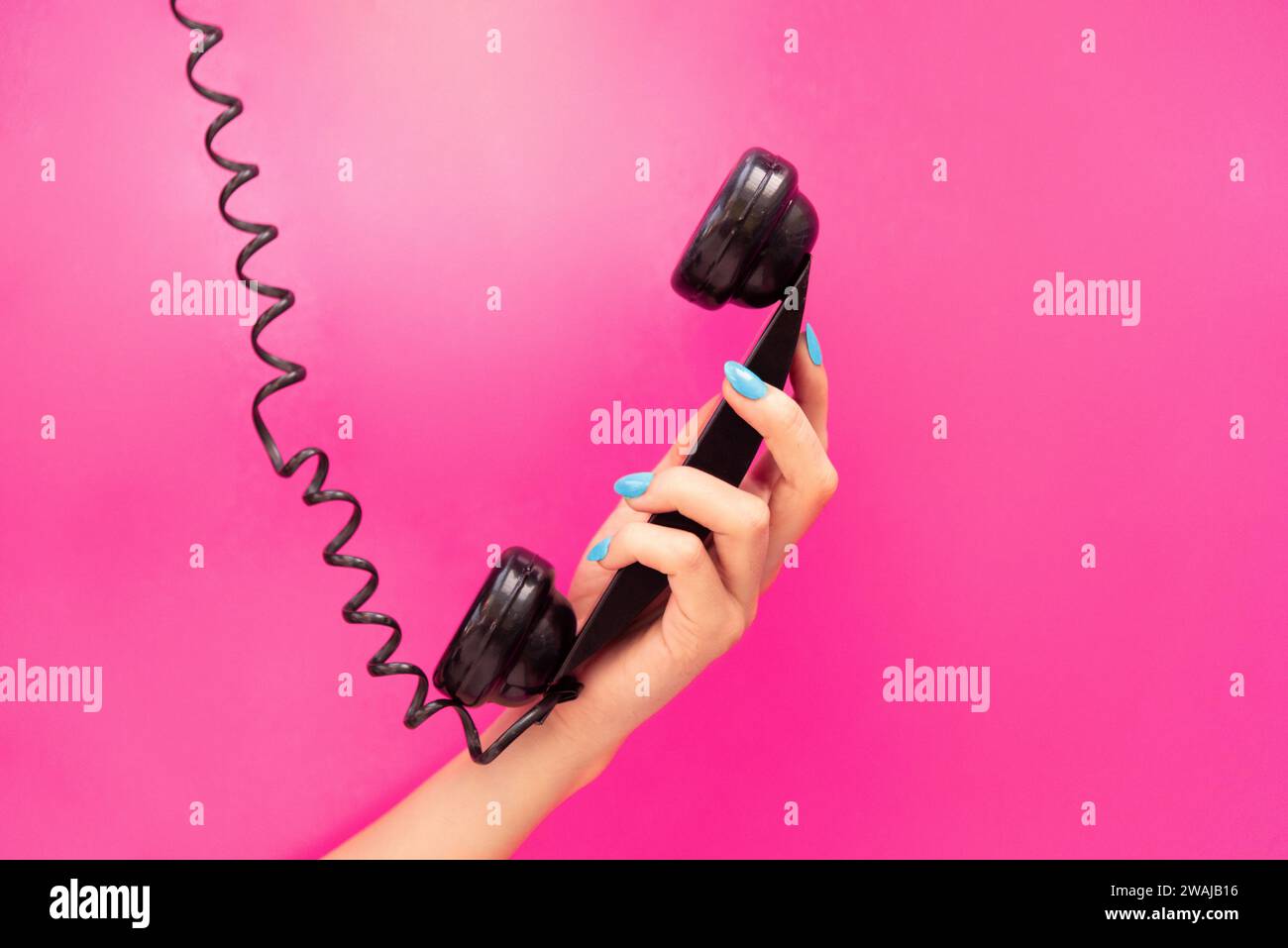 Anonymous woman's hand with blue nail polish holding a black telephone ...
