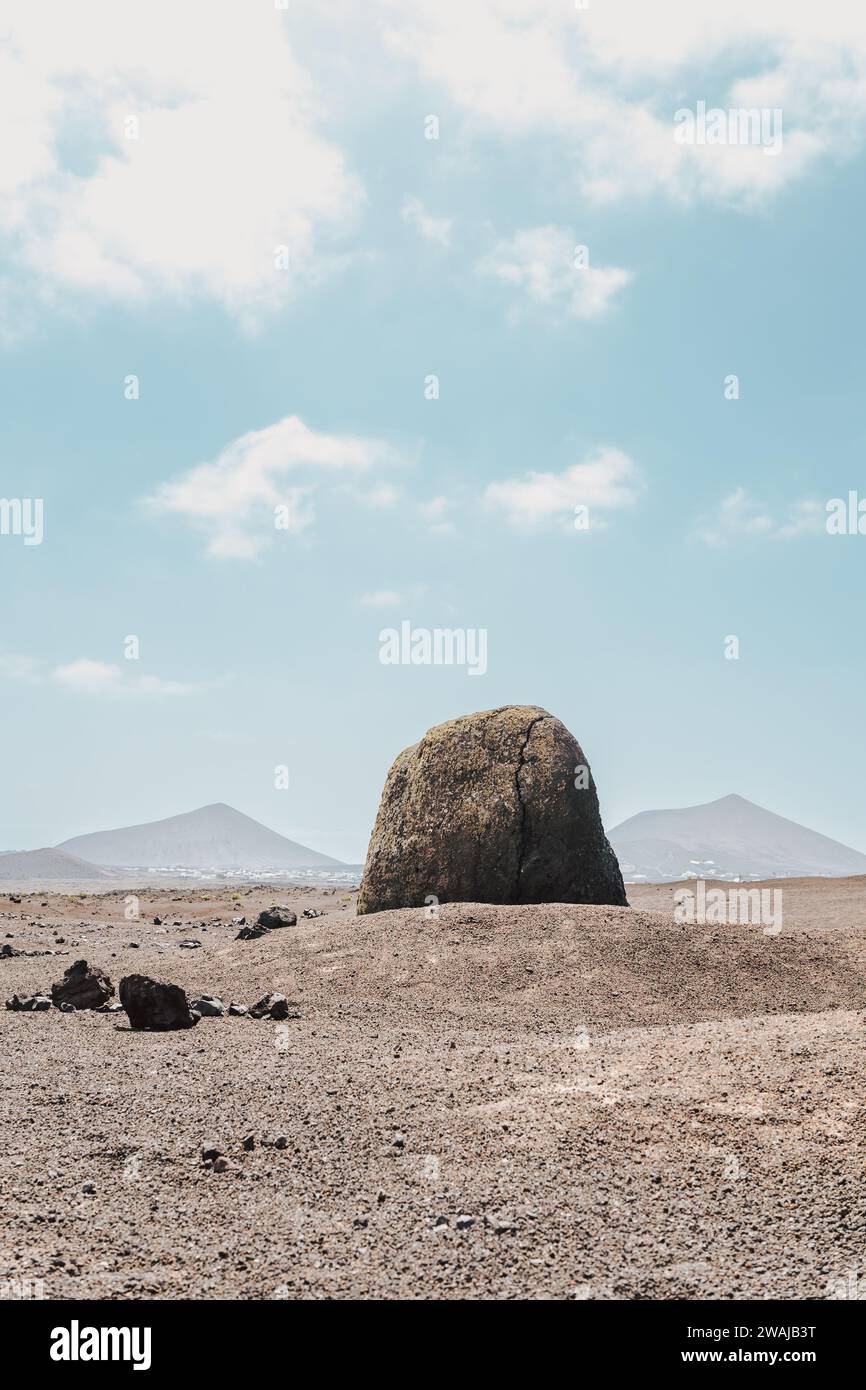 A solitary weathered boulder stands prominently on the barren desert ...