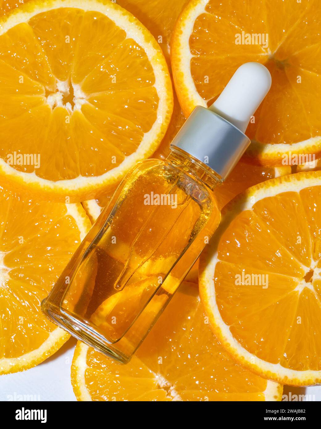Top view of a golden hued face serum bottle surrounded by vibrant ...