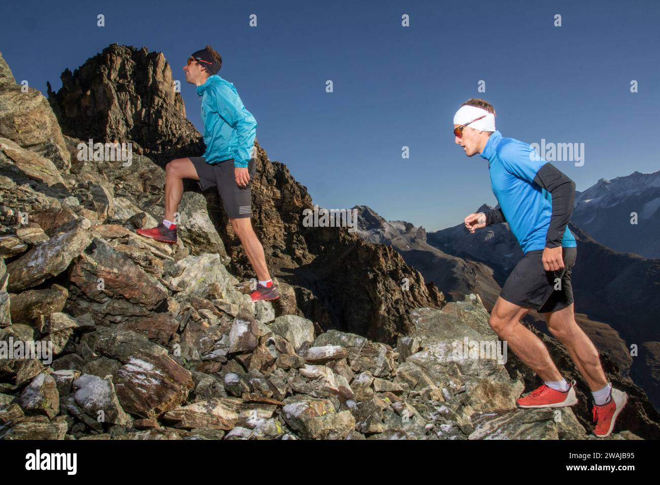 Side view of two trail runners in coordinated athletic wear jogging on ...