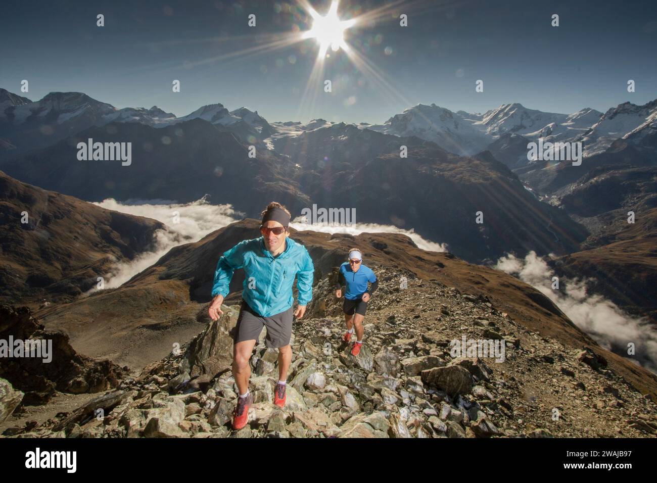 Two trail runners in coordinated athletic wear jogging on a steep rocky ...