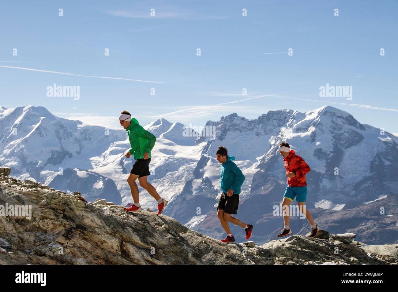 Side view of three runners in sportswear jogging on a high mountain ...