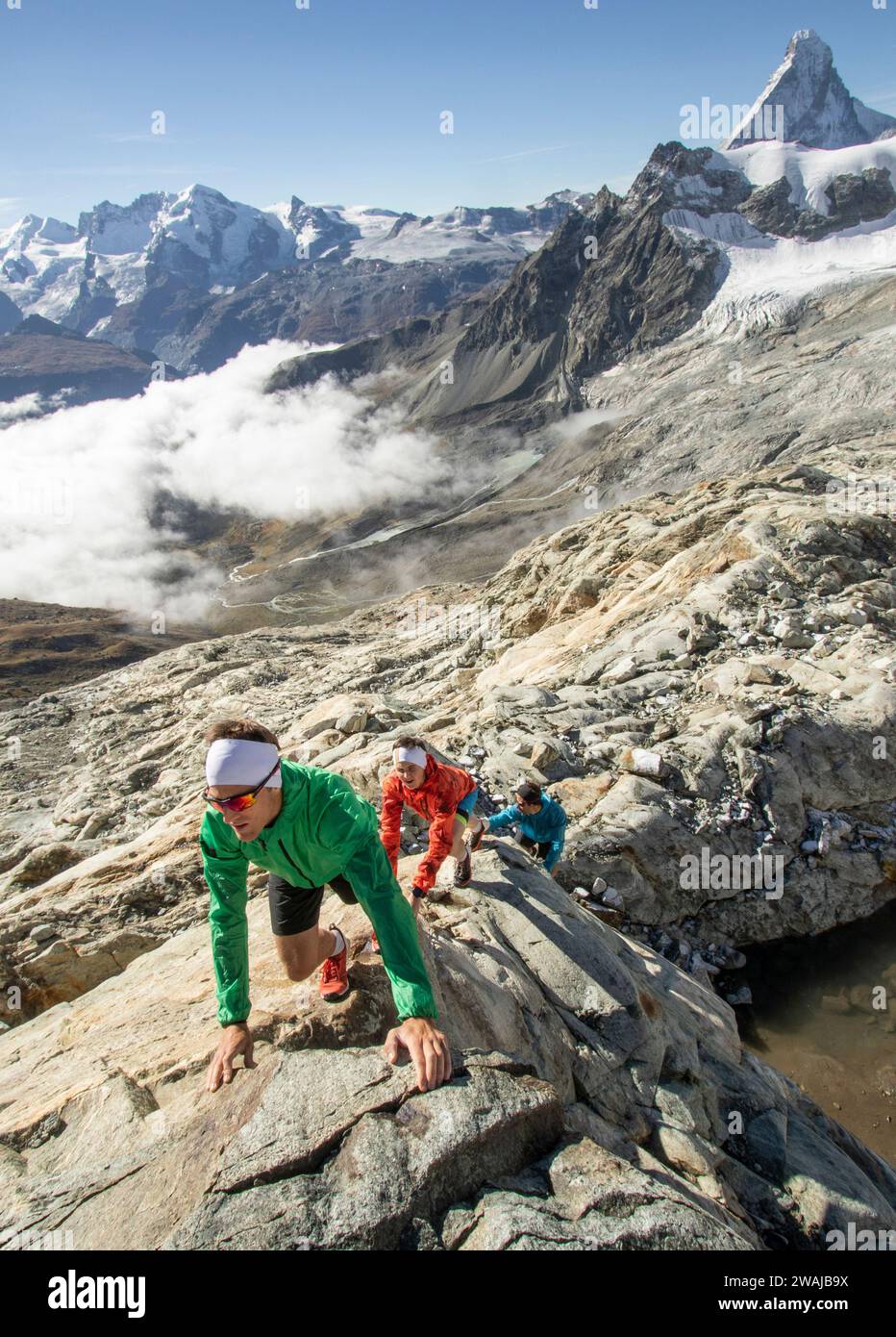 From above of three climbers in colorful gear ascending a steep rocky ...