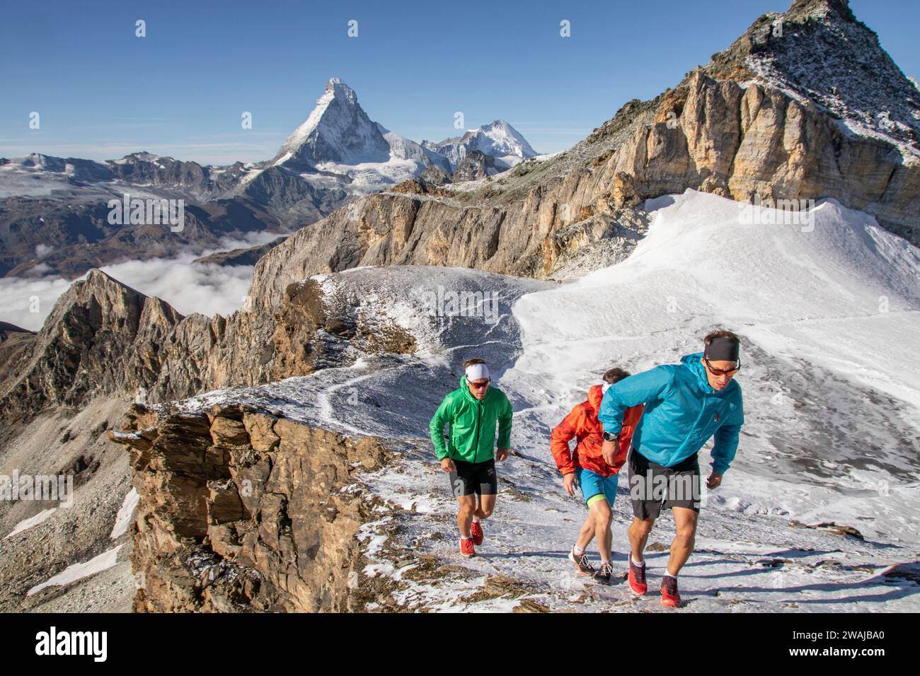 Top view of three trail runners in colorful attire running on a snowy ...
