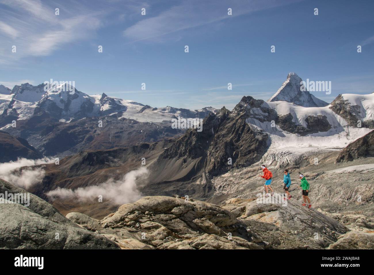 Three trail runners moving swiftly across a rocky alpine landscape with ...