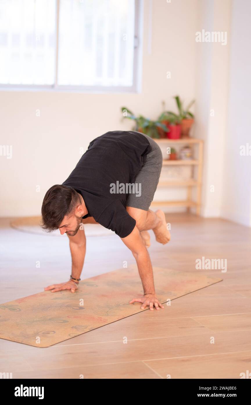Focused guy in activewear balancing on hands on mat during practice in ...
