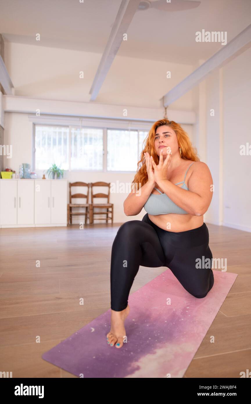 Full body of focused plus size lady in sportswear kneeling and ...