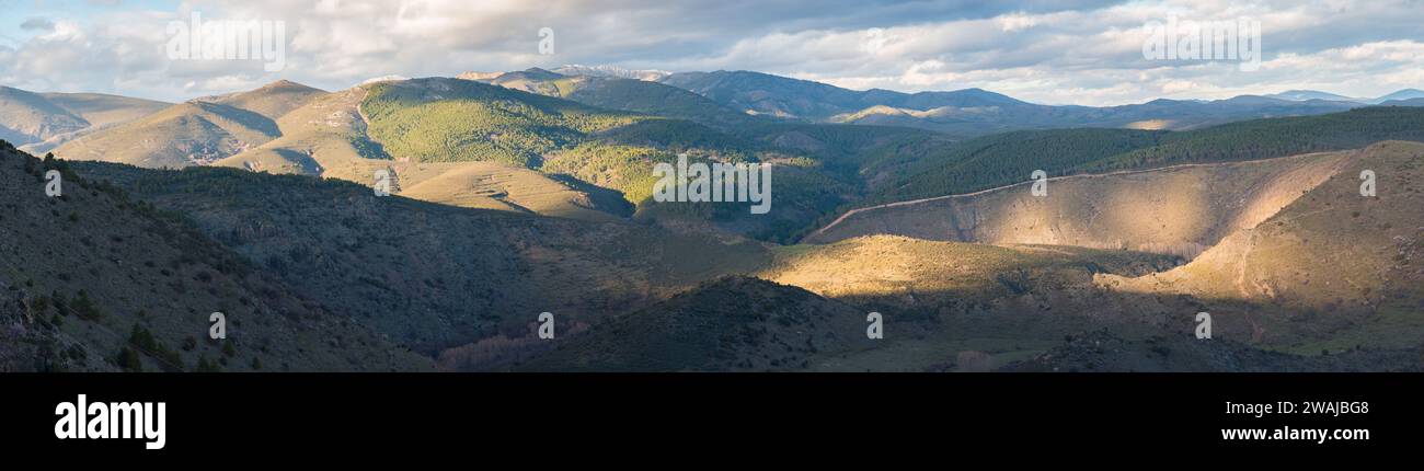 A panoramic view of mountainous terrain bathed in golden sunlight with ...