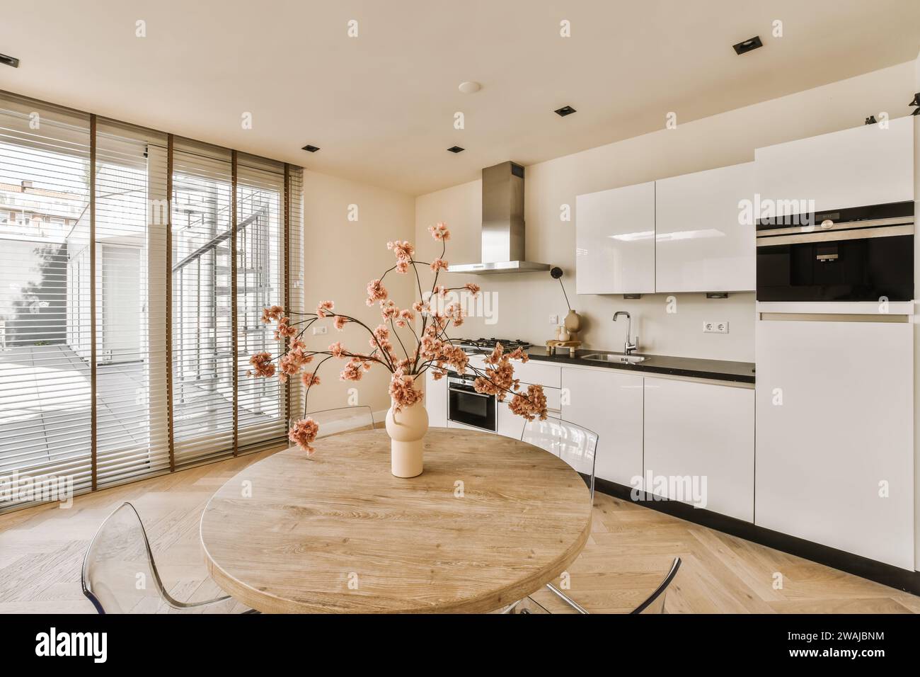 Dining table with chairs arranged in front of modern white kitchen by ...