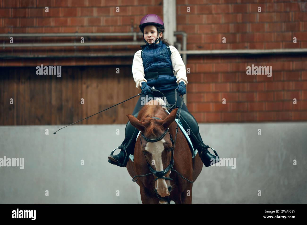 Little girl, child in uniform and helmet sitting on horse, raining ...