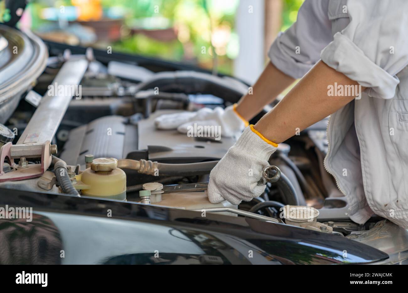 Mechanic use wrench tighten engine nut on race car in his home garage ...