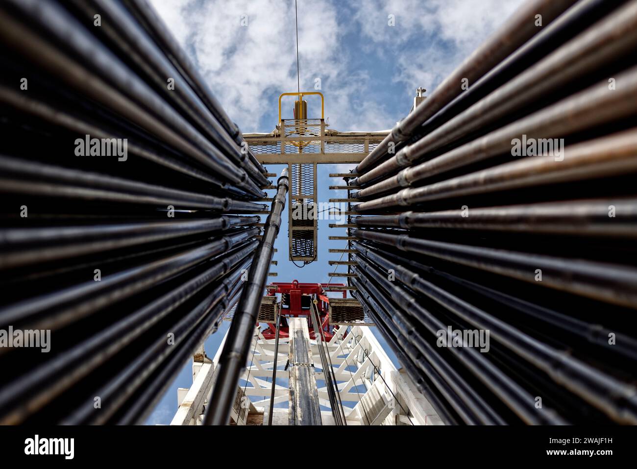 A view of an oil rig from below, with a stack of drilling pipes in the ...