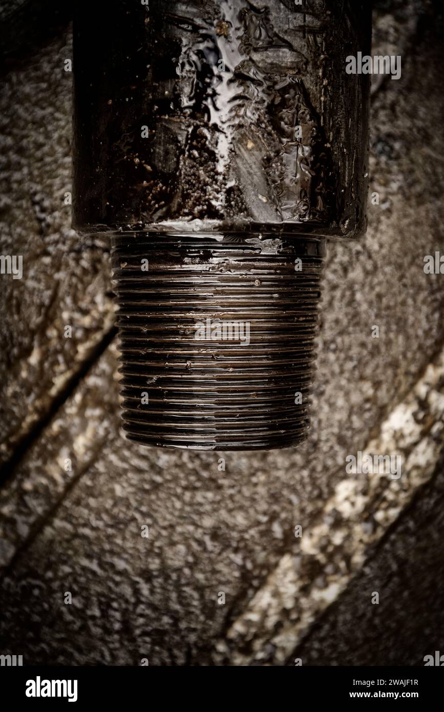 A close-up of an oil-covered drilling pipe connection, with a shiny ...